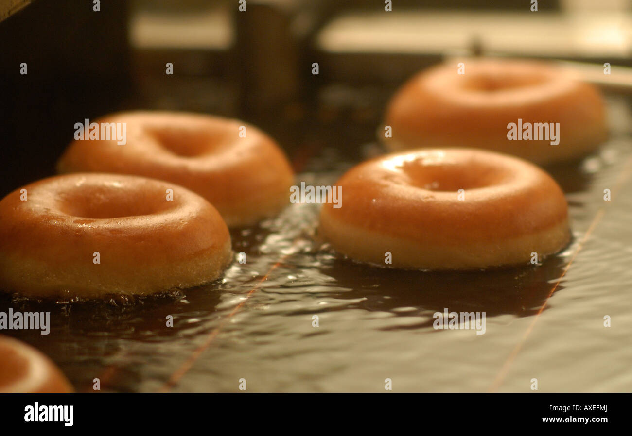 A doughnut assembly line as freshly made doughnuts float to the glazing ...