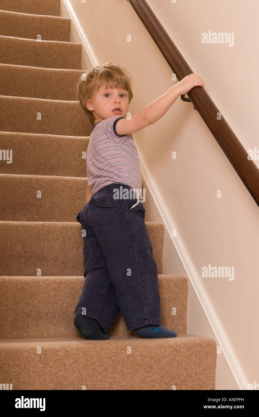 two year old boy climbing the stairs carefully holding on to the ...
