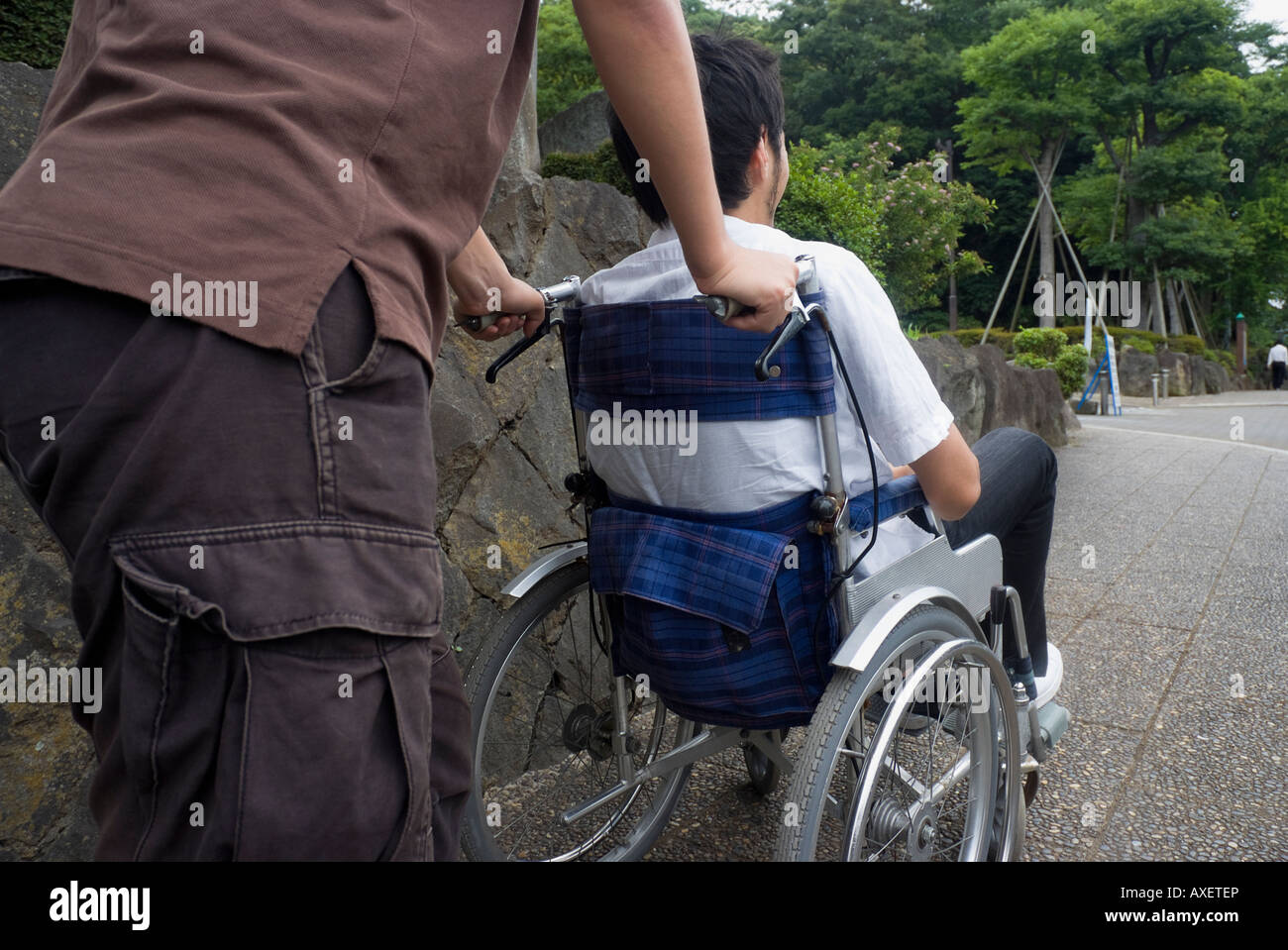 Young man pushing man on wheelchair Stock Photo - Alamy