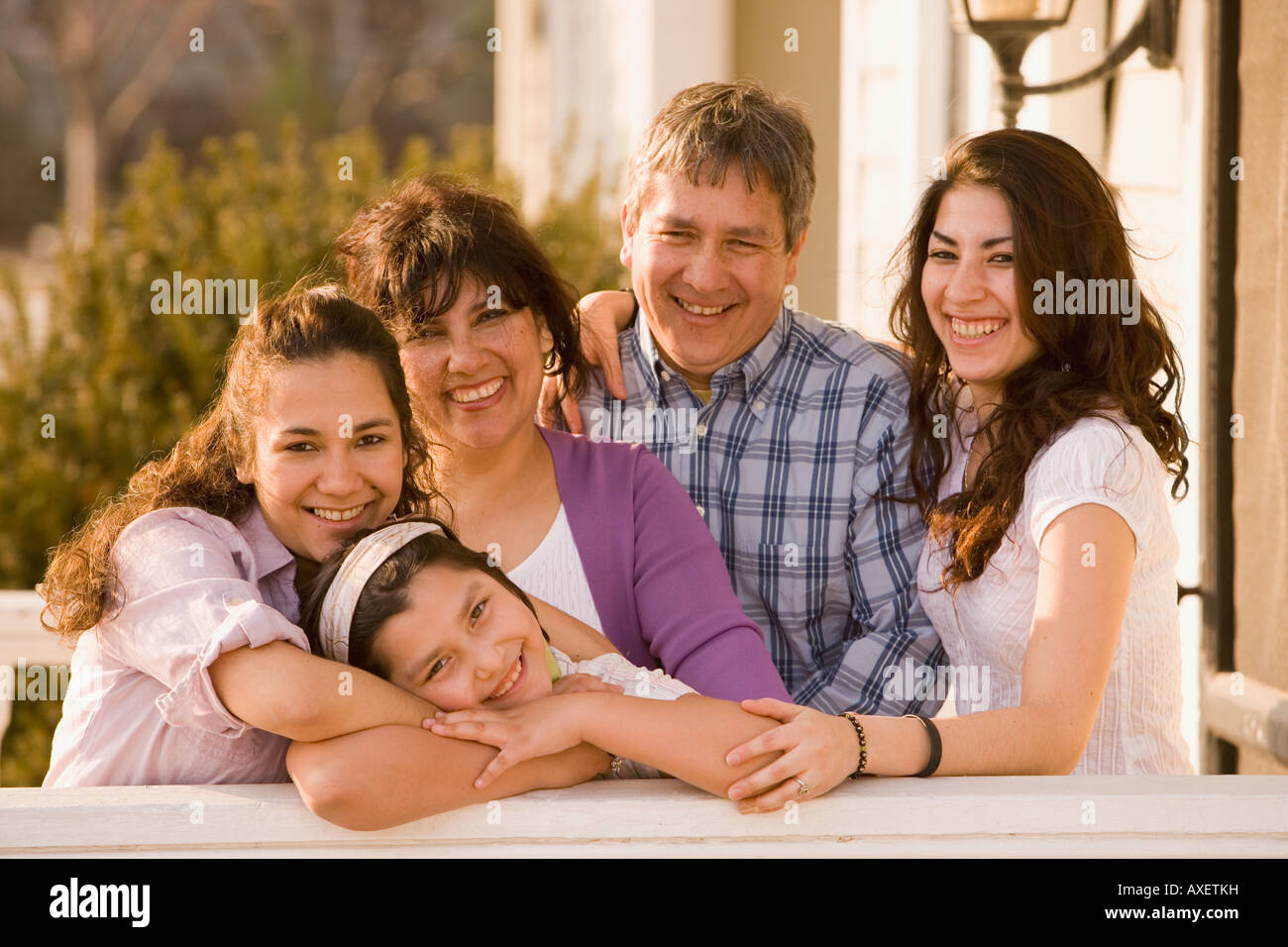 Hispanic family hugging on porch Stock Photo - Alamy