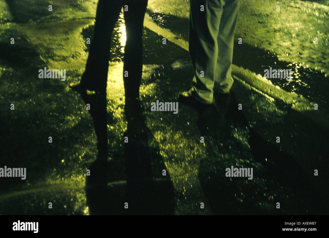 woman female man male couple wait stand outdoor open air night puddle ...