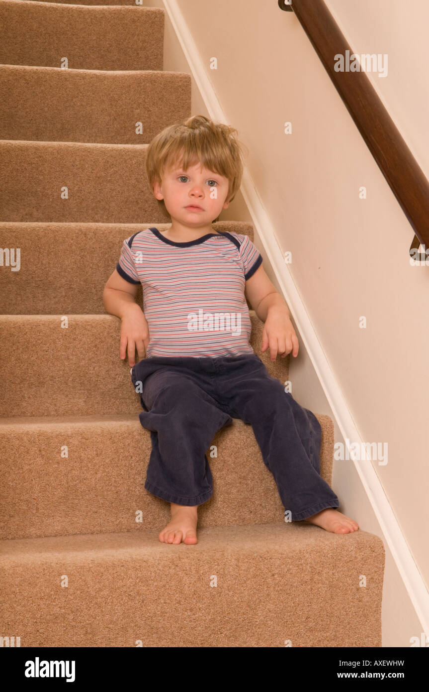 two year old boy sitting at bottom of stairs perhaps as part of ...