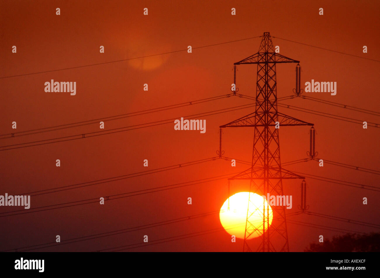 An electricity pylon with the sun setting behind Stock Photo - Alamy