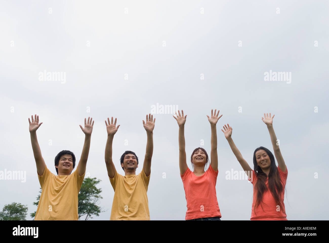 Four people standing with arms raised Stock Photo - Alamy