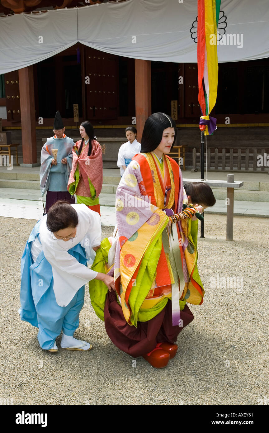 A servant helps a woman dressed in Heian period costume at the Gokusui ...