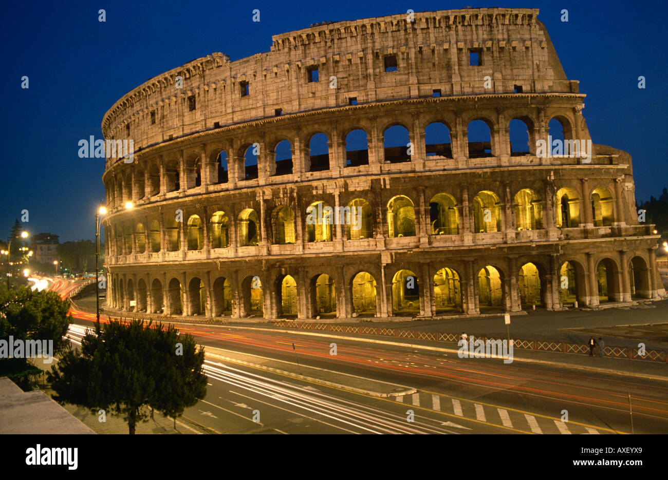 Traffic streaks past a floodlit Roman Colosseum on Via dei Fori ...
