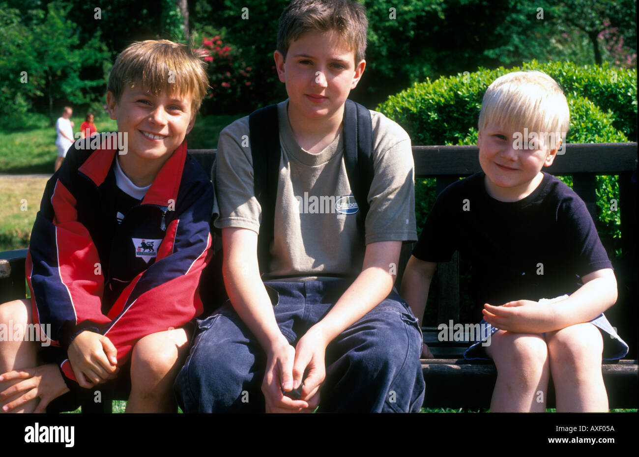 Three brothers sitting on bench in the park Stock Photo - Alamy