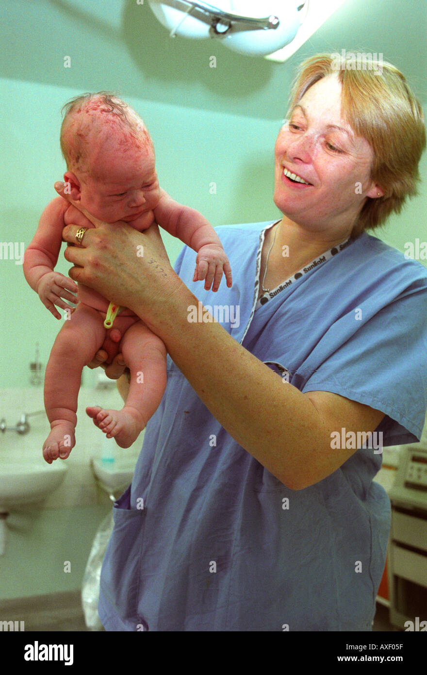 Midwife holding up newborn baby to be checked and weighed Stock Photo ...