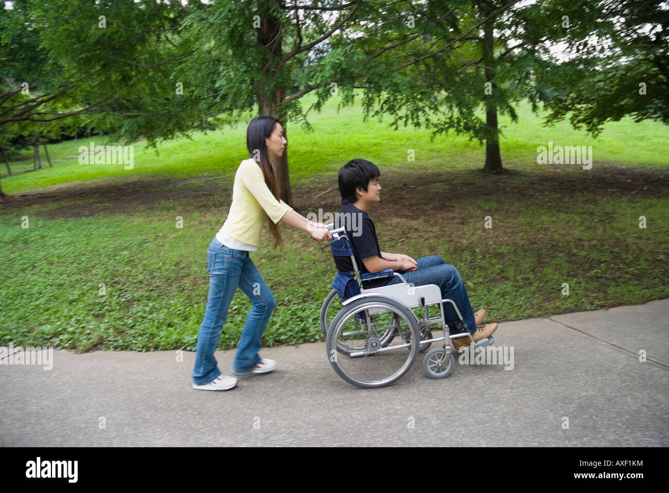 Young woman pushing man on wheelchair Stock Photo - Alamy