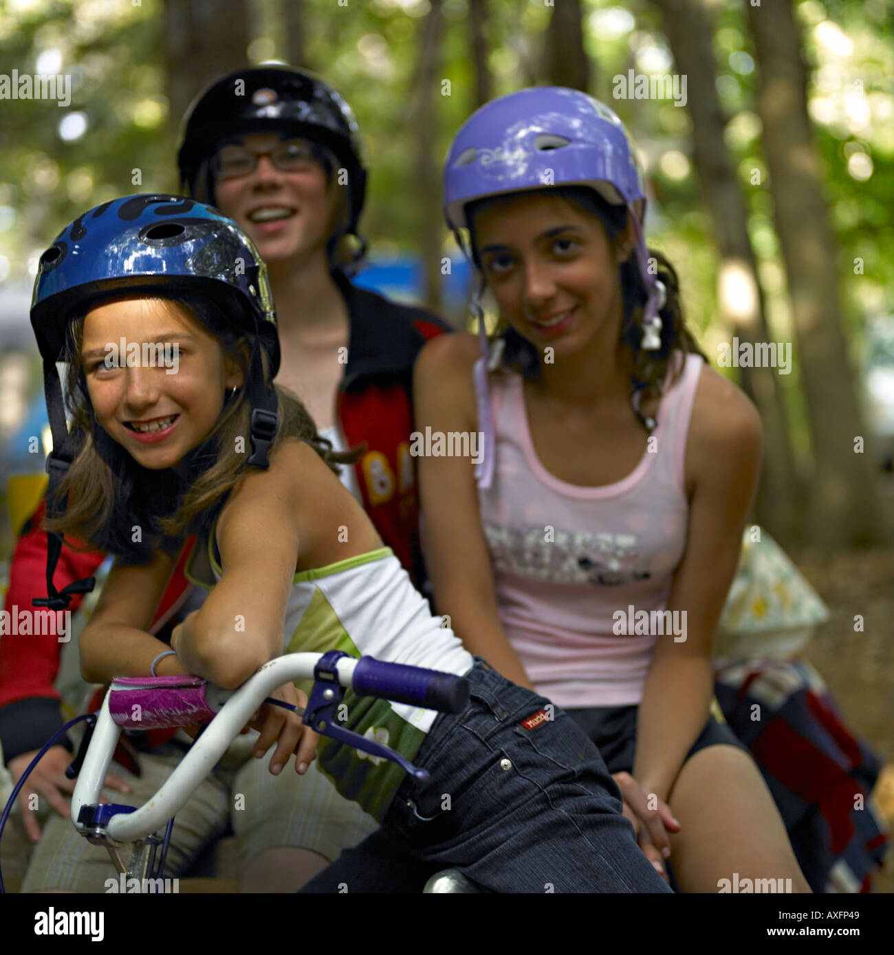 Three girls in helmets posing in the woods Stock Photo - Alamy