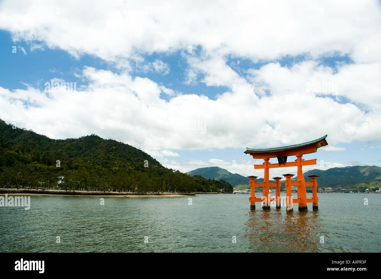The floating torii gate of Miyajima is reflected in the water at high ...