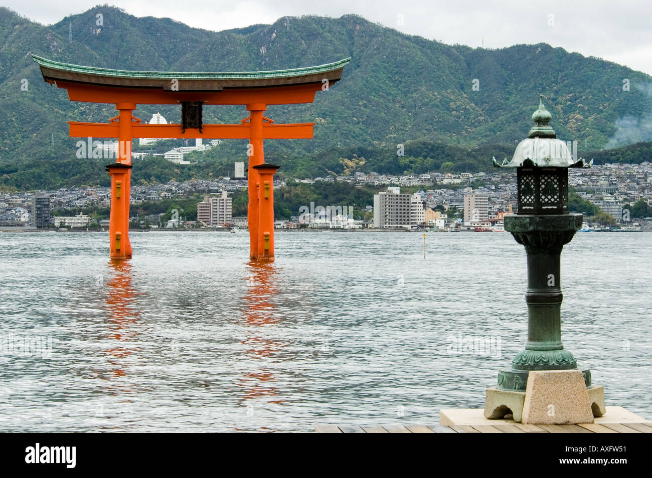 The floating torii gate of Miyajima is reflected in the water at high ...
