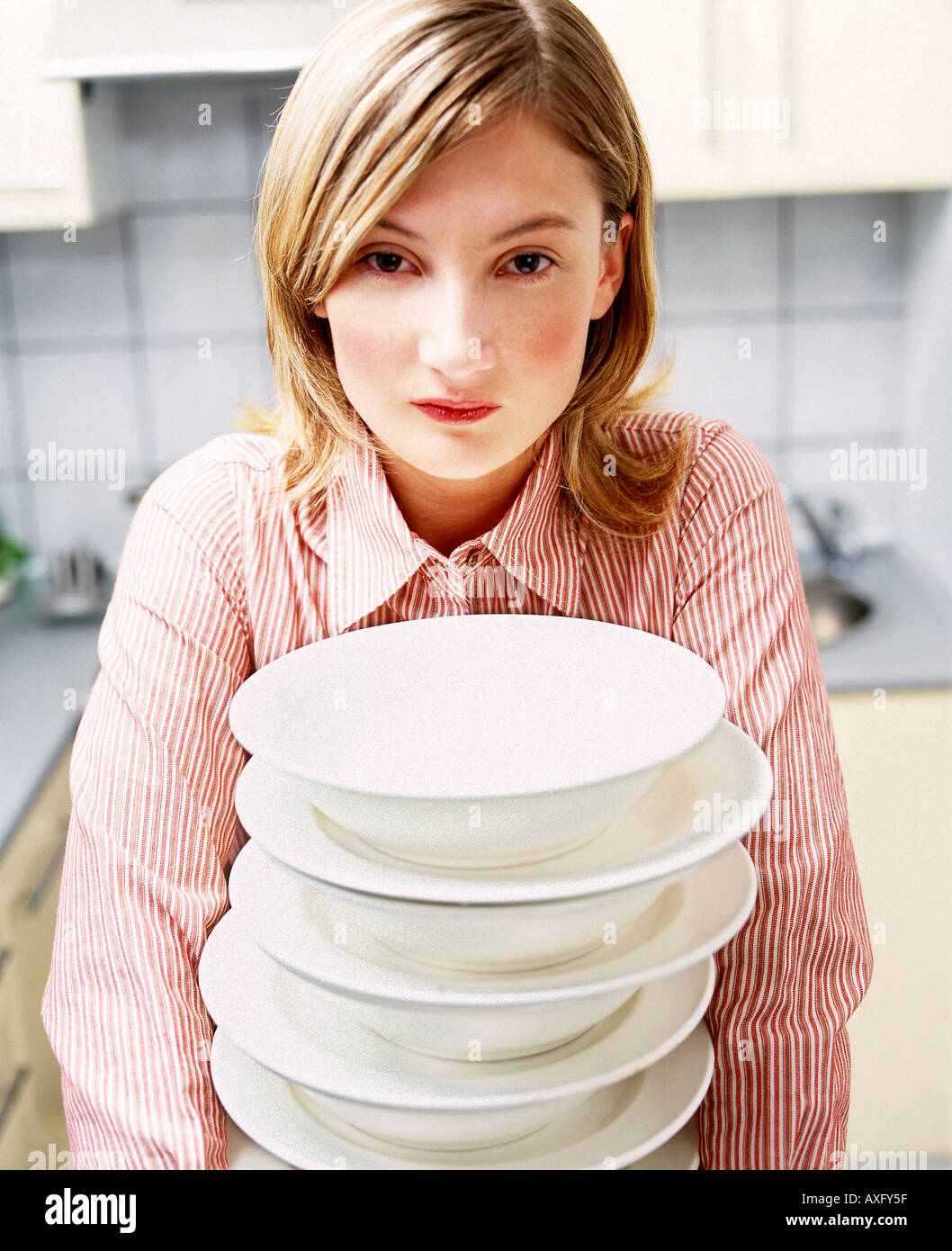 Woman in kitchen carries a stack of plates Stock Photo - Alamy
