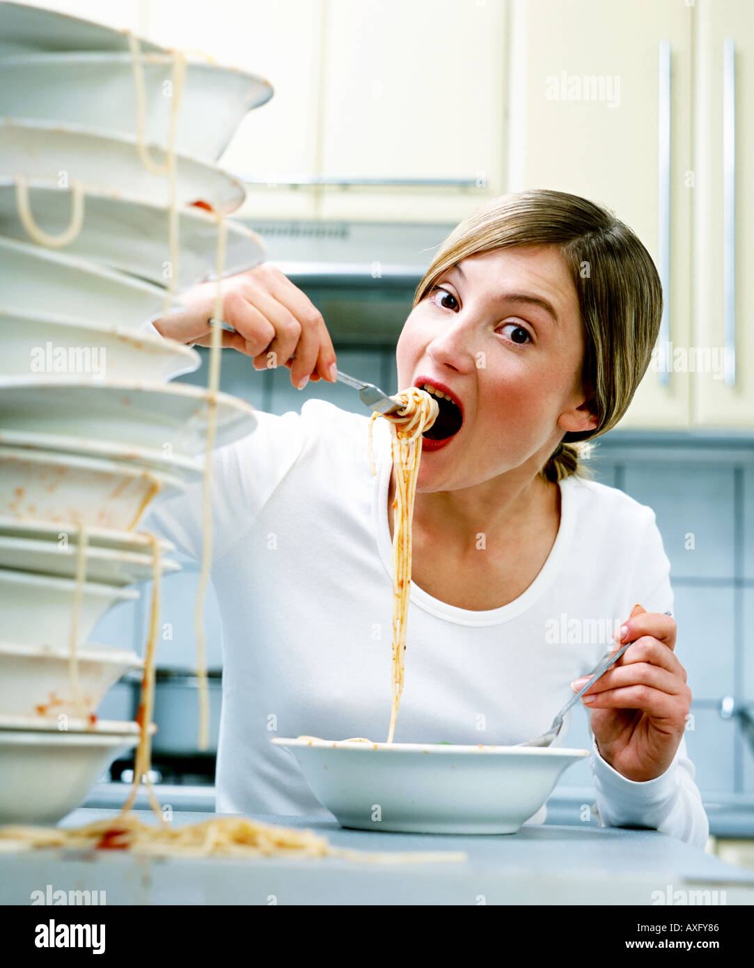 Young woman eating spaghetti next to the stack of dirty plates Stock ...