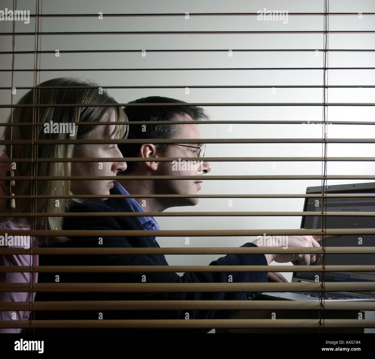 Man and woman review something on their laptop computer behind window ...