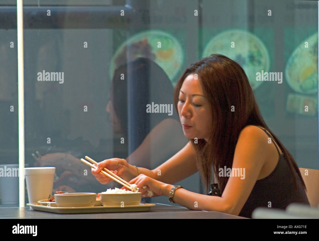 An Asian woman eating alone with chopsticks in a Sydney restaurant ...
