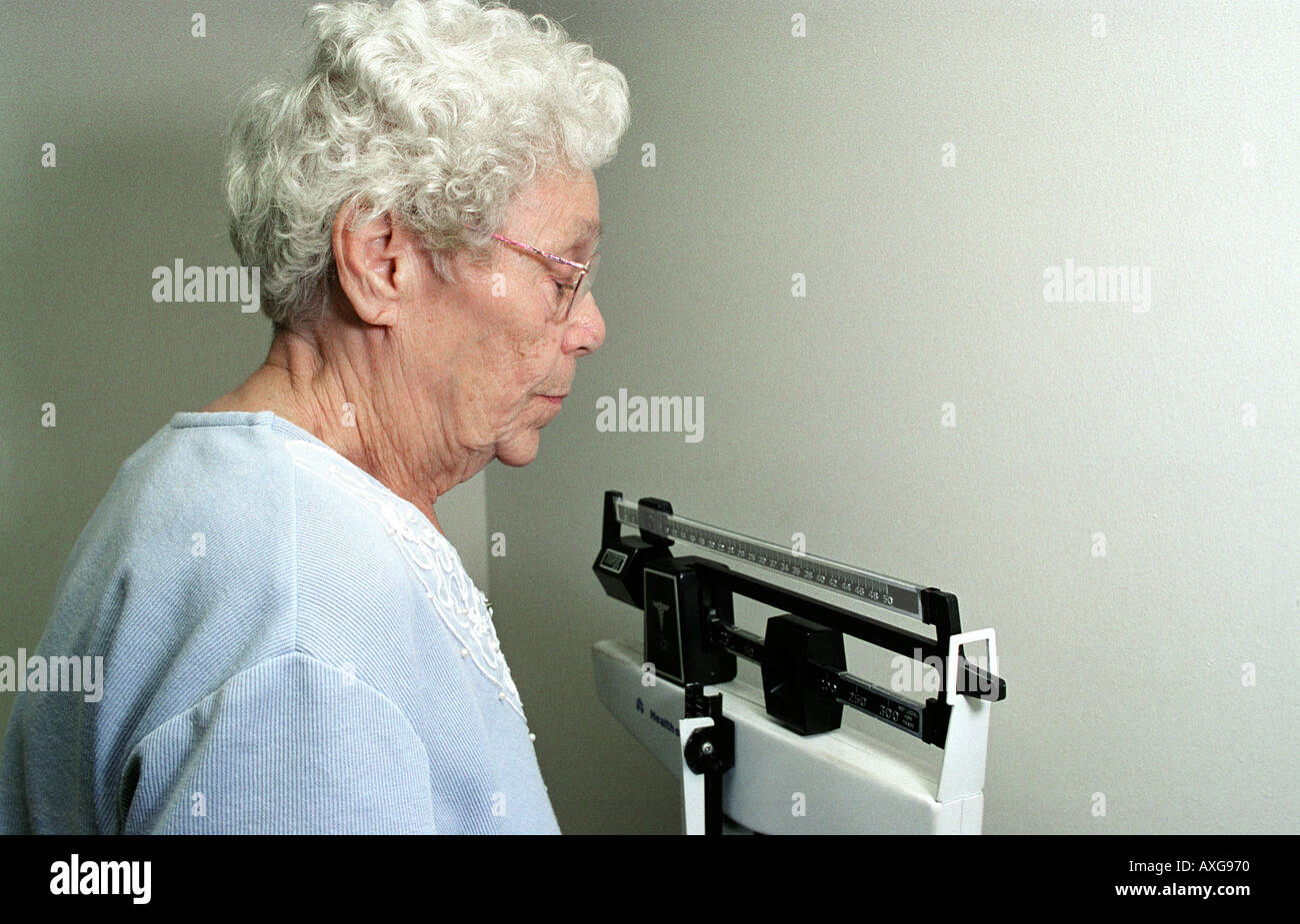 82 year old senior female checks her weight on scale and exercises to ...