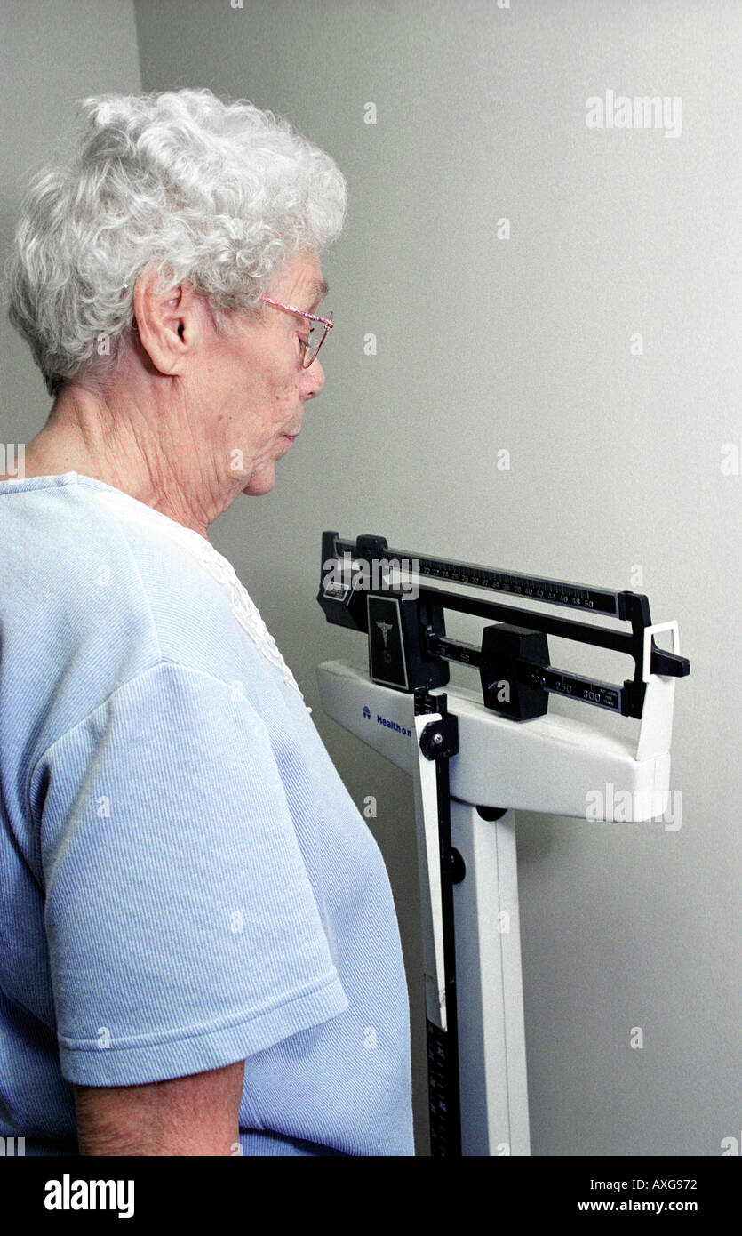 82 year old senior female checks her weight on scale and exercises to ...