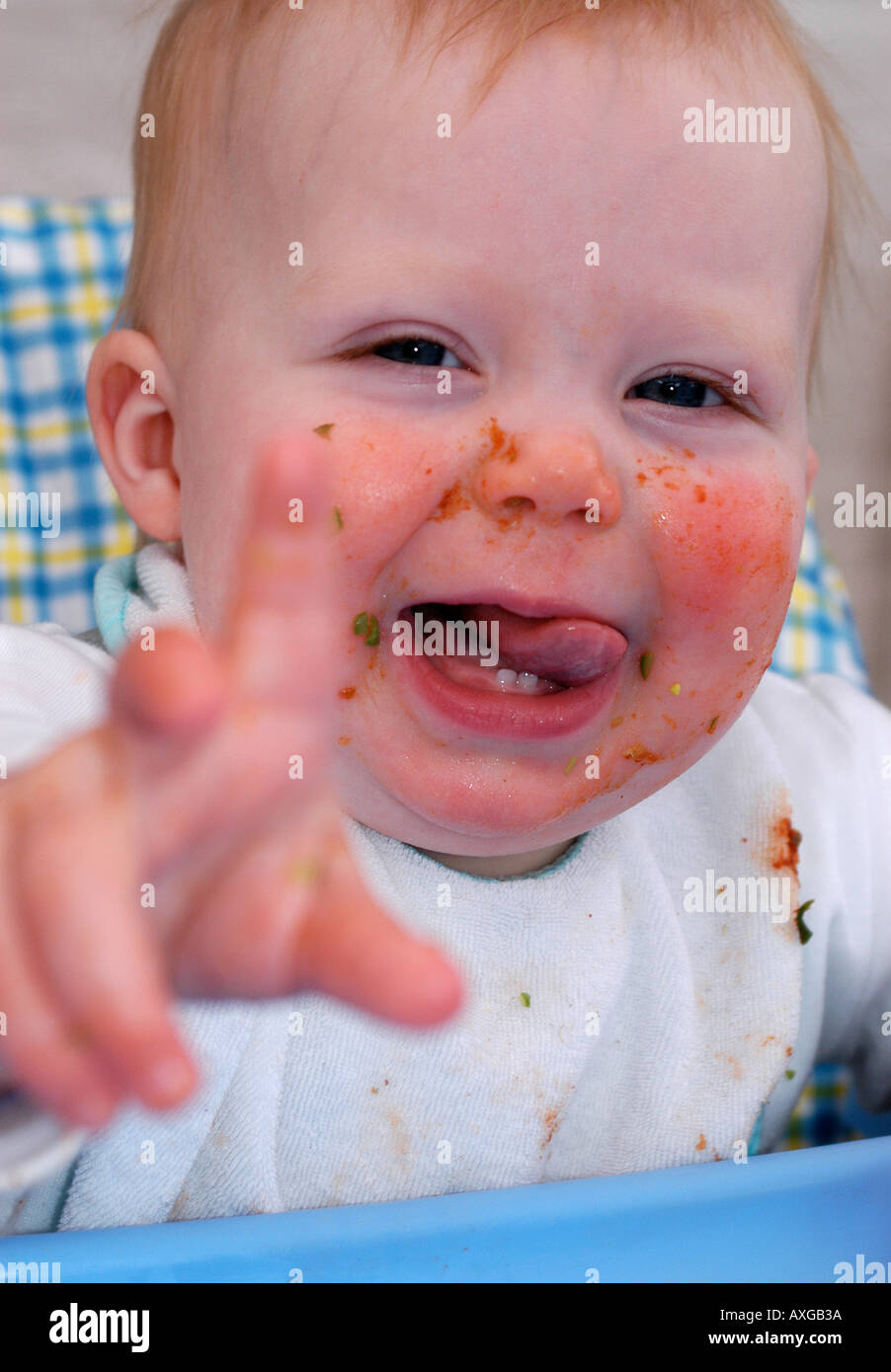 one year old baby girl eating a messy lunch reaching out Stock Photo ...