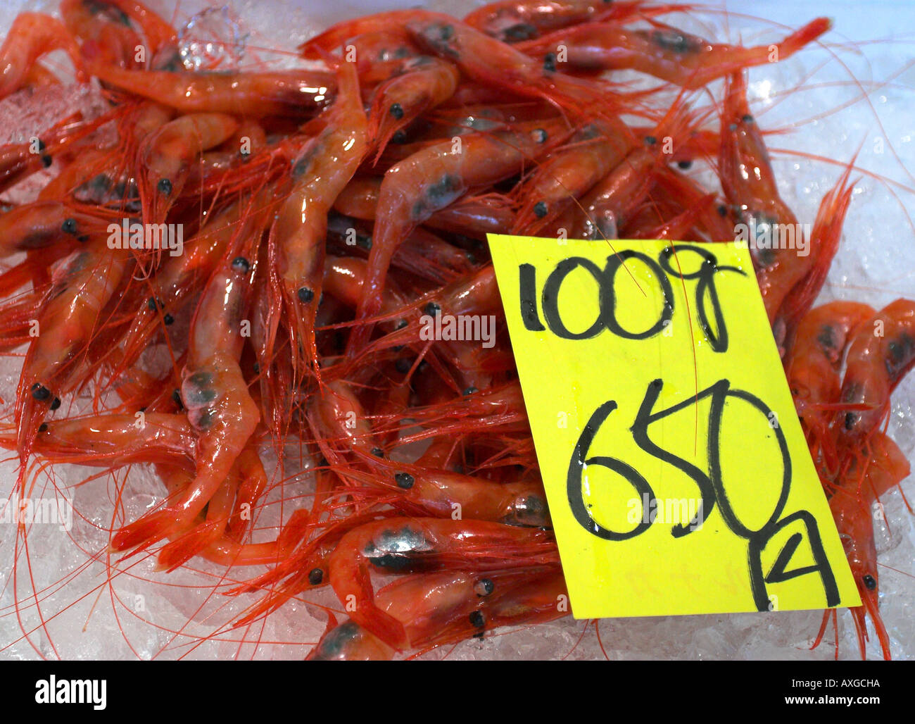 Orange shrimp/prawn on ice with a yellow price tag on a market stall at ...