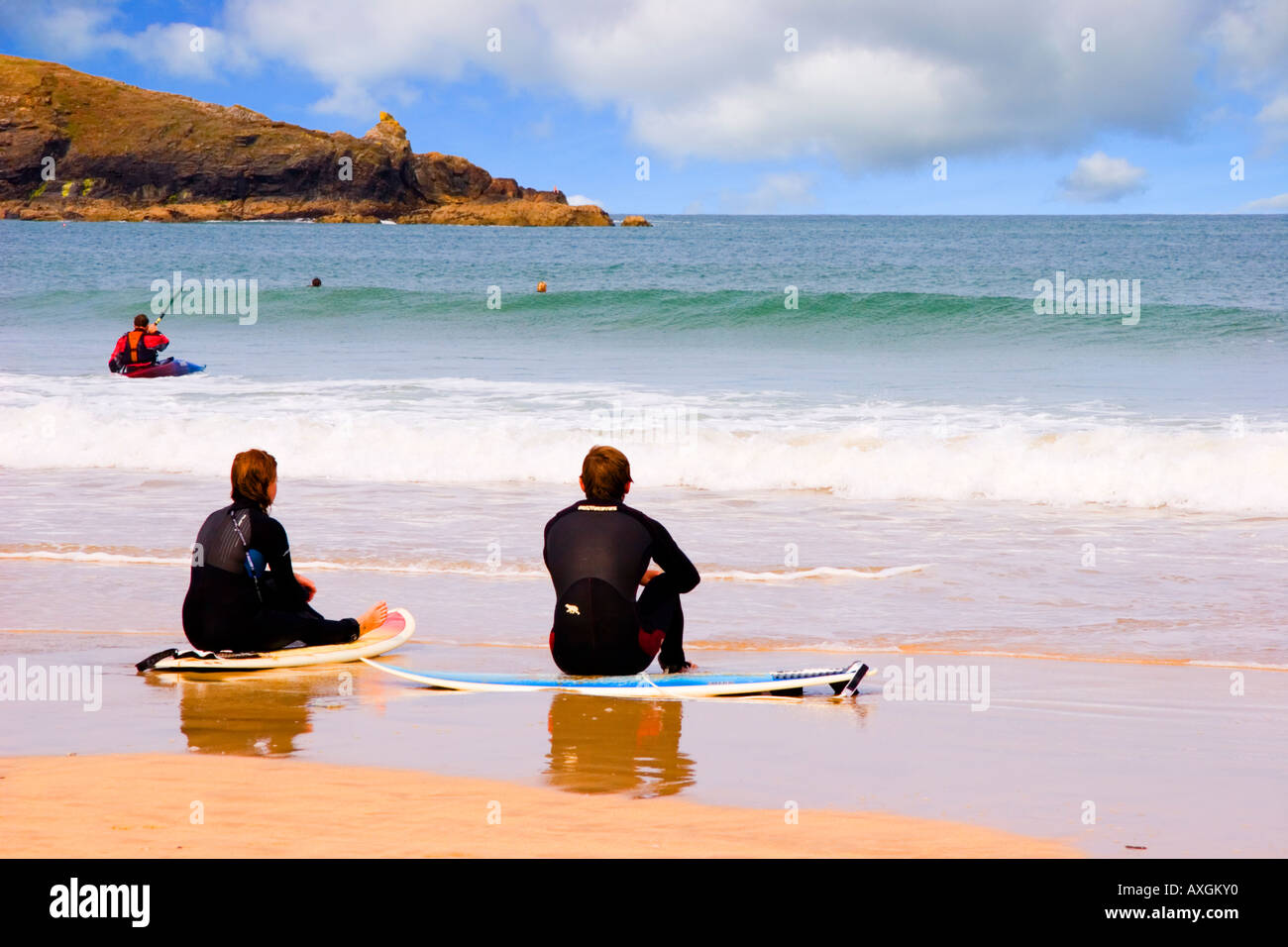 Two surfers sitting on the beach at Harlyn Bay Cornwall England UK ...