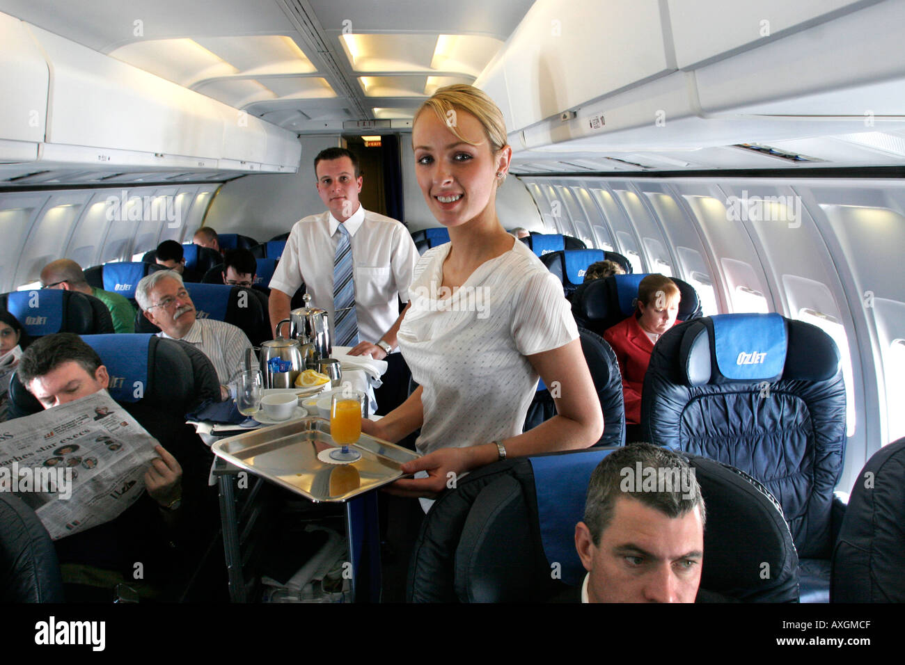 Flight attendants serve refreshments in a business class cabin on a ...