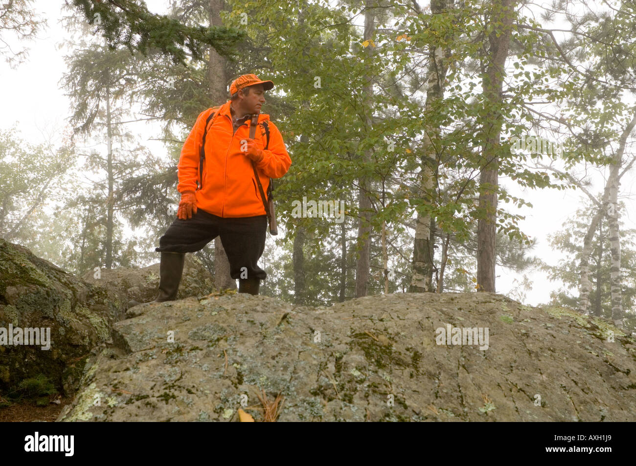 A DEER HUNTER IN BLAZE ORANGE WITH RUGER MODEL ONE RIFLE ON HIS BACK ...