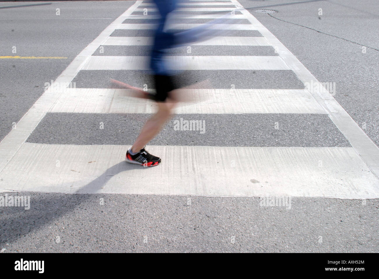 Using a slow shutter speed the leg and feet of a runner are blurred as ...