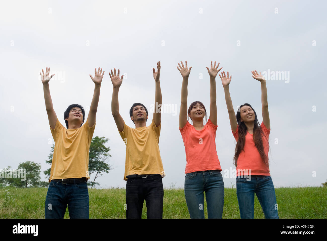 Four people standing with arms raised Stock Photo - Alamy
