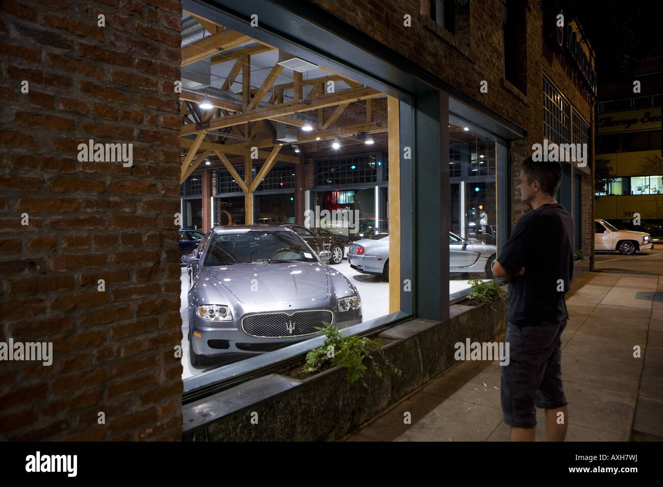 Man looking through window of luxury auto dealer Stock Photo - Alamy