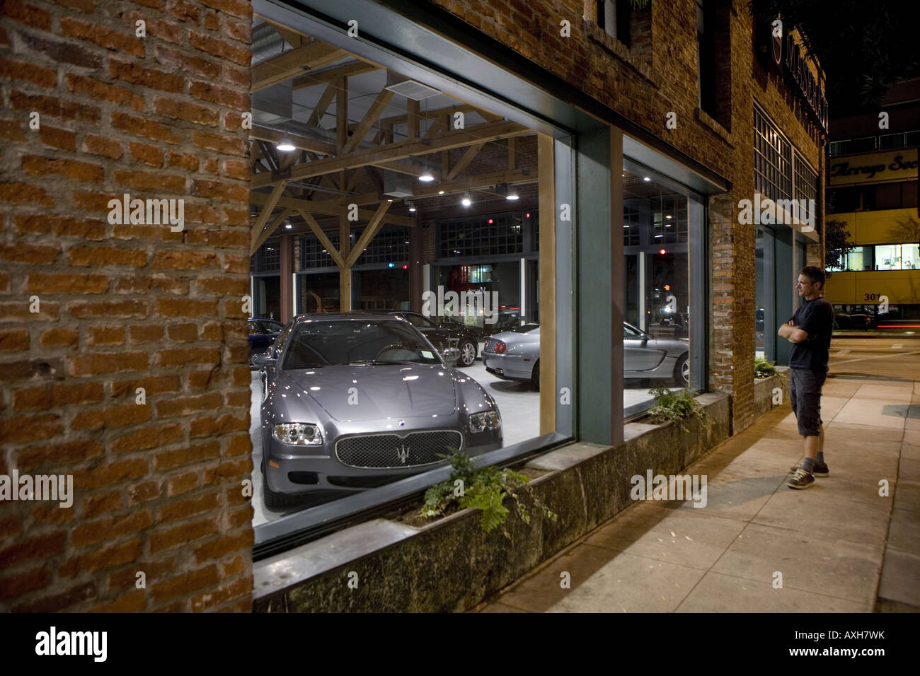 Man looking through window of luxury auto dealer Stock Photo - Alamy