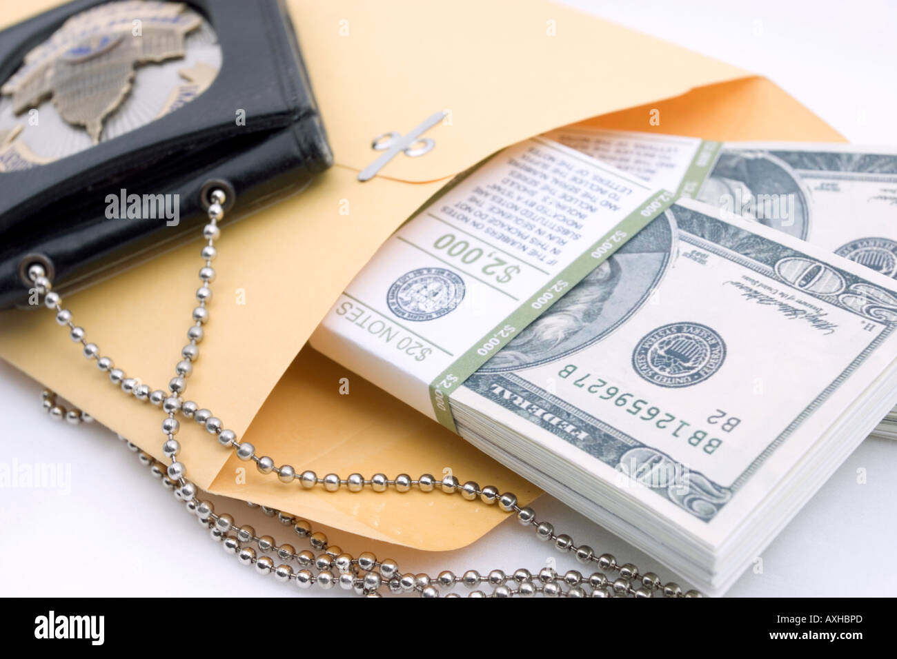 Police badge on top of open envelope containing two bundles of cash ...