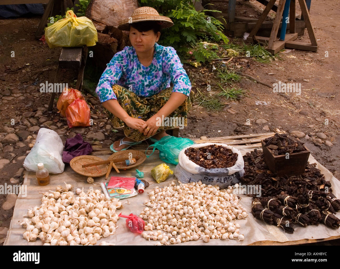 Stock photograph of a young woman selling garlic and cassia seed pods ...