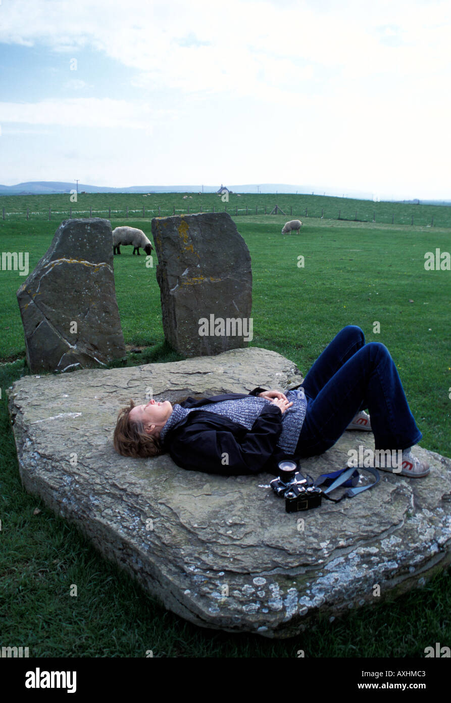 A woman lying on a huge prostrate slab her cameras resting next to her ...