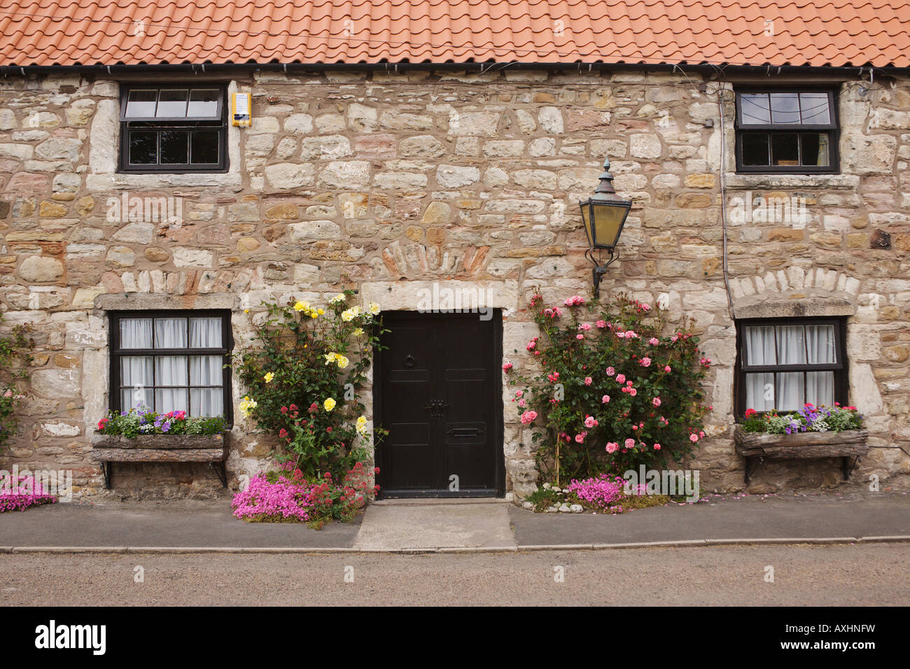 Pretty stone cottage with climbing roses and flowers in wndow boxes ...
