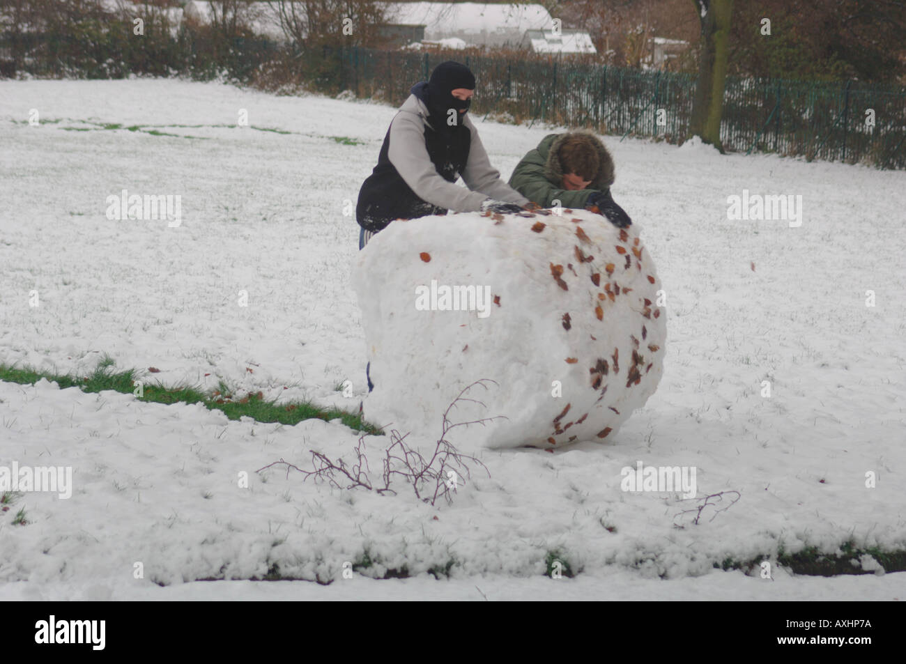Teenage Lads Rolling A Giant Snowball Stock Photo - Alamy