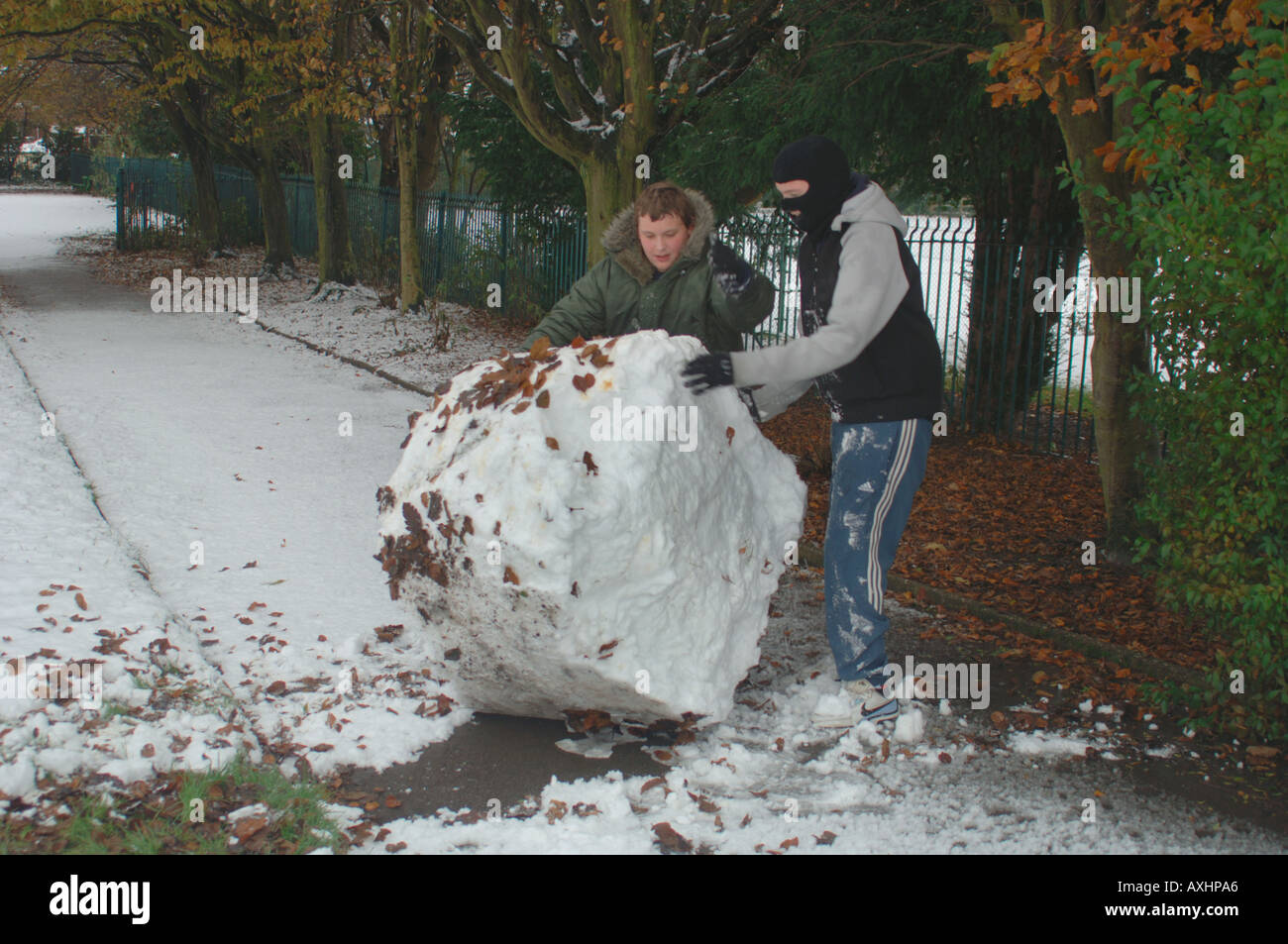 Teenage Lads Rolling A Giant Snowball Stock Photo - Alamy