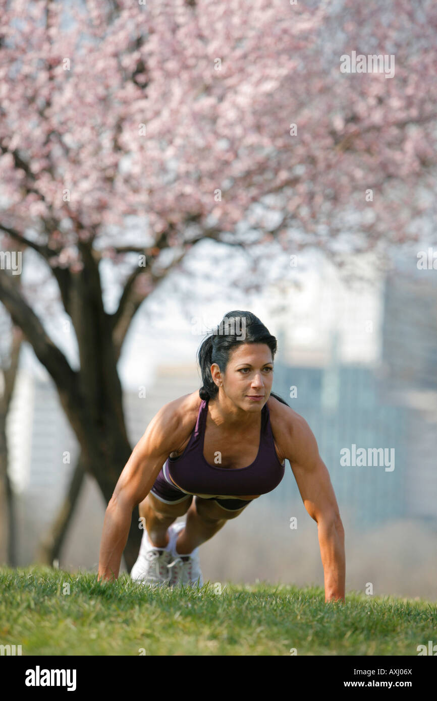 Woman athletic age 45 doing push-ups outdoors, Cherry Blossoms ...