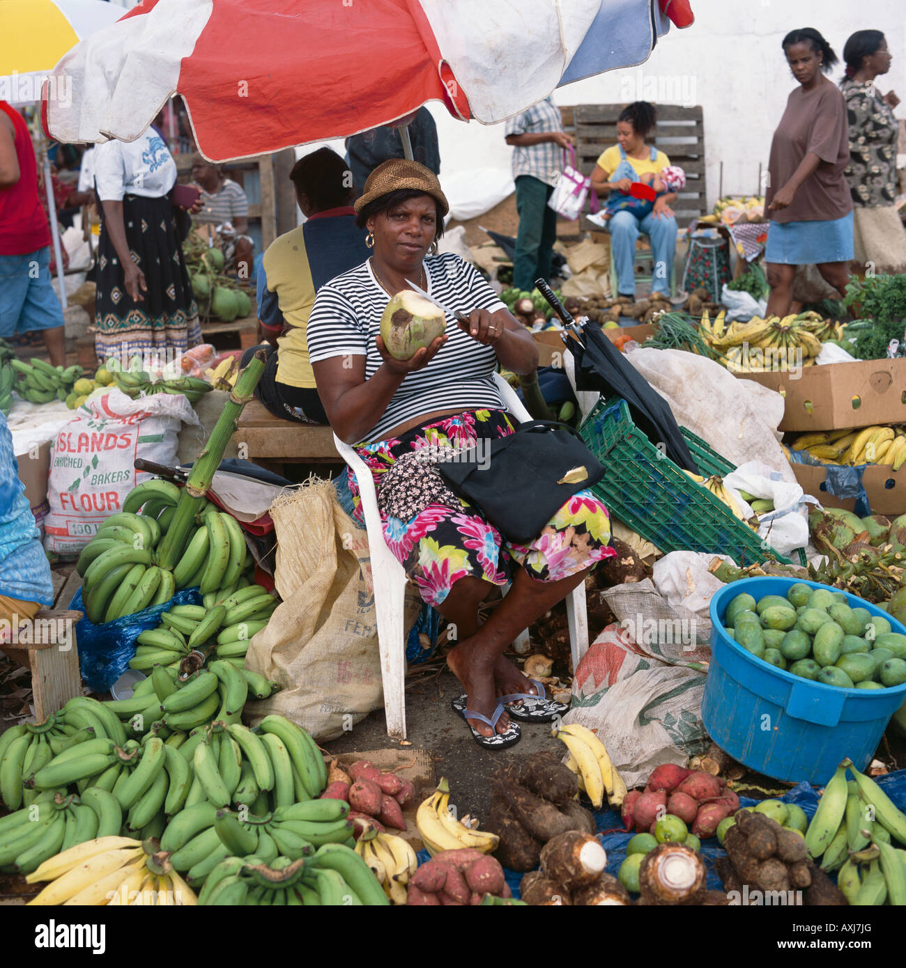 Local ethnic market with lady sat at her stand amongst green bananas on ...