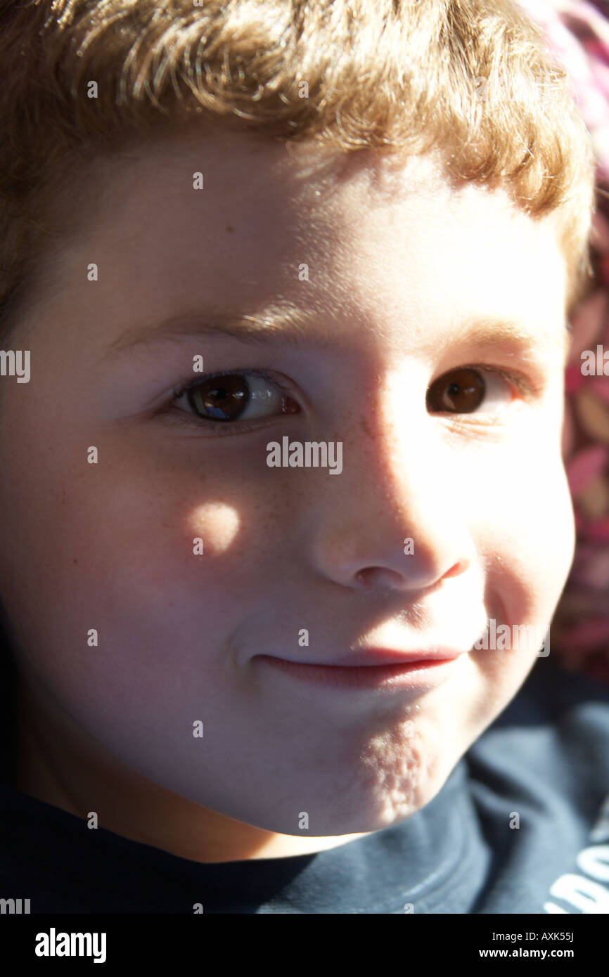 Young boy child with sunlight on far side of face making a silly face ...