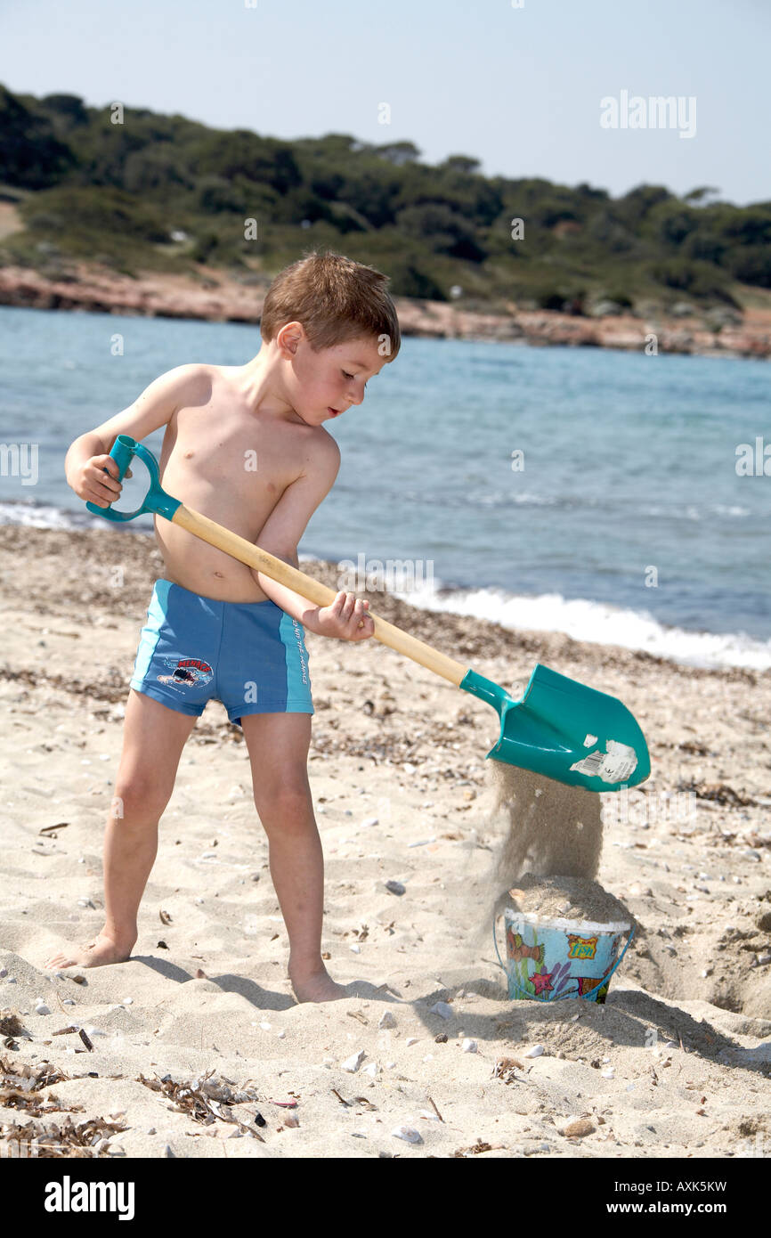 Boy playing with bucket and spade in the sand hi-res stock photography ...