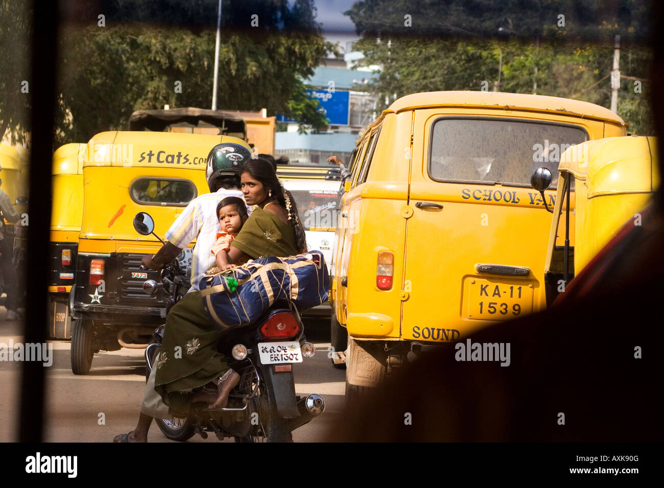 A family sits on a motorbike among rickshaws in the rapidly growing ...