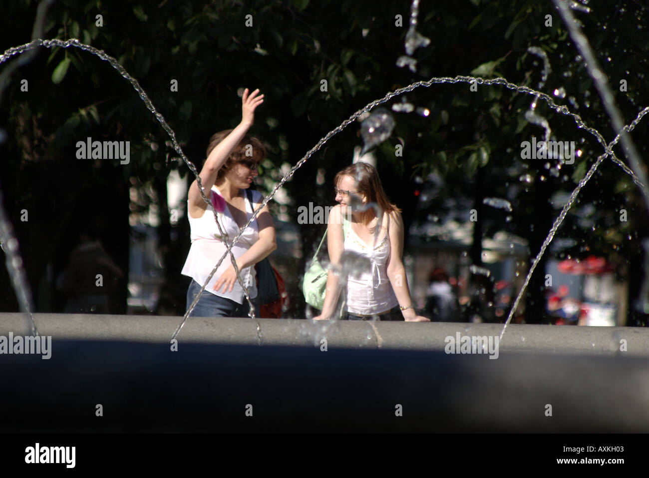 Two girls at fountain talking Stock Photo - Alamy