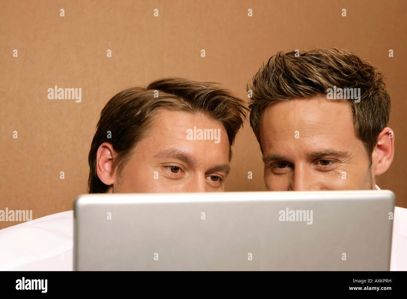Two businessmen using laptop, heads behind the screen Stock Photo - Alamy