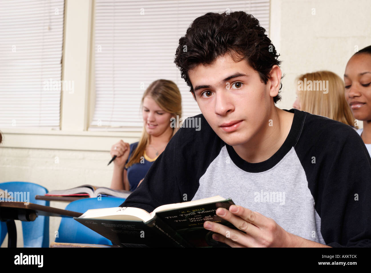 Stock Photograph of a teen in class looking up from reading a book ...