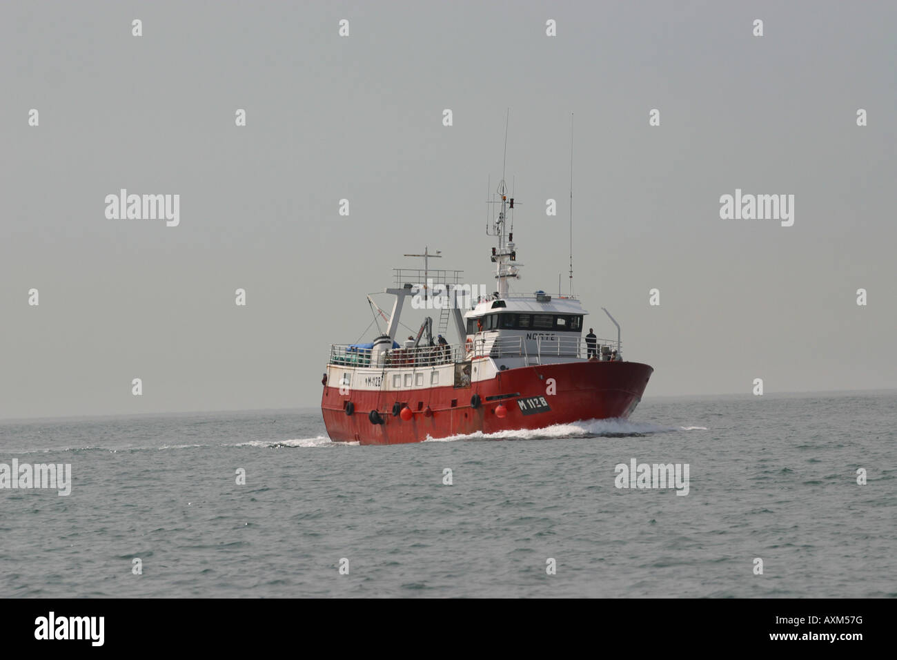 Red trawler boat at speed front profile bow, white cabin green sea ...