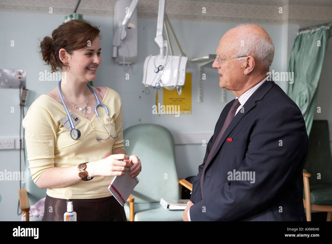 Female trainee junior doctor smiling and talking to a senior doctor on ...