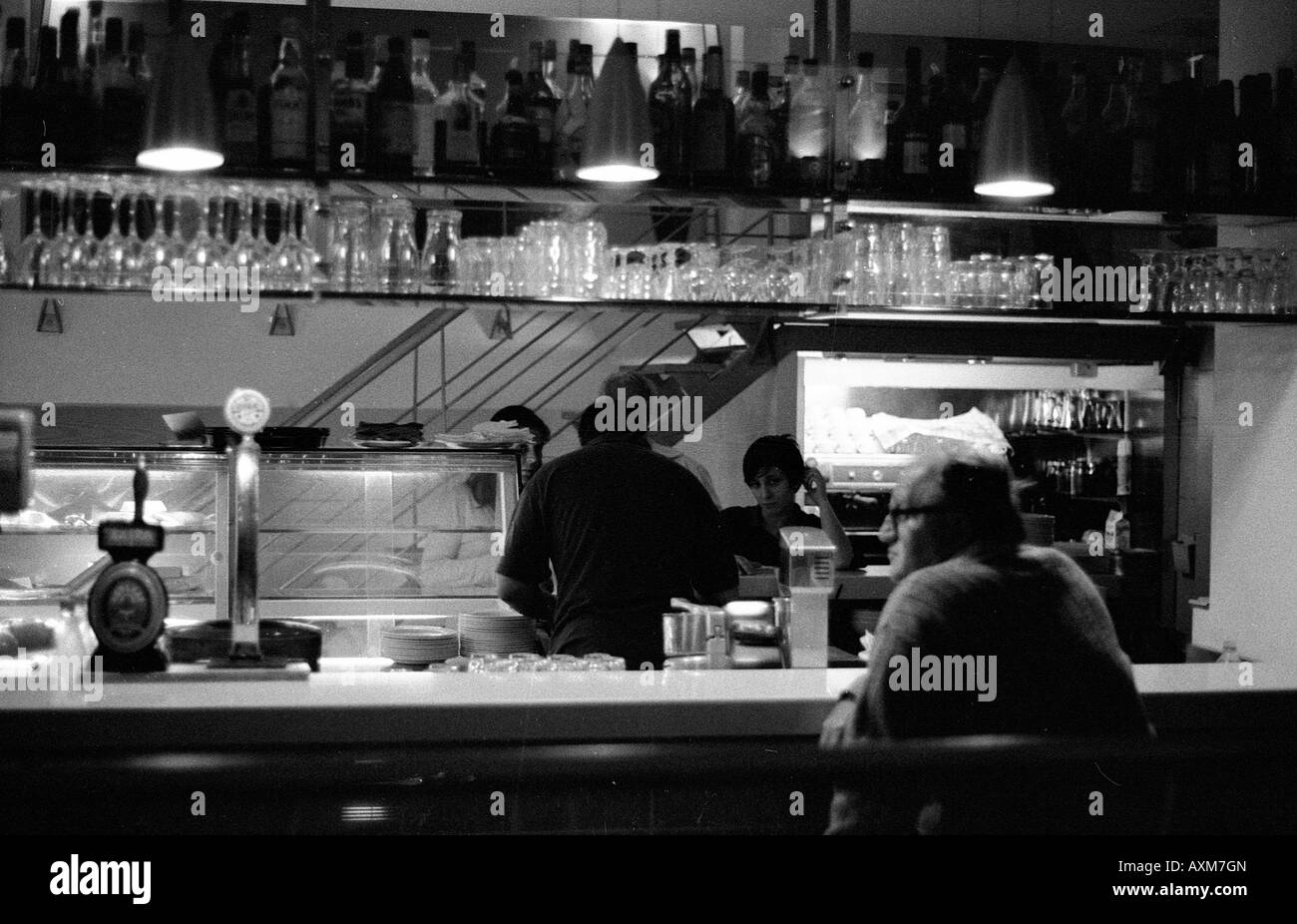 portrait of a lonely man drinking in a bar with the waitress looking ...