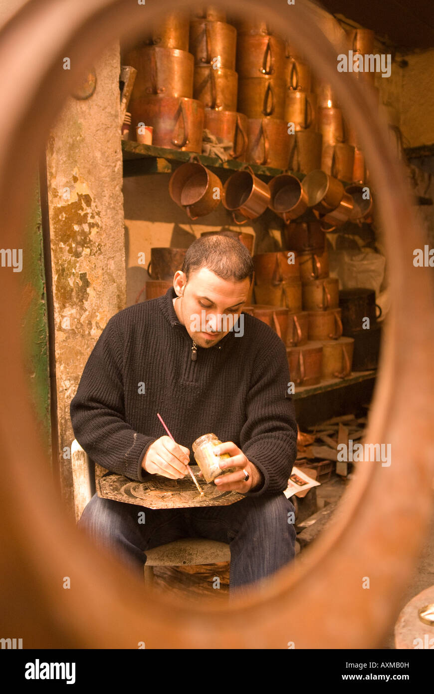 Artisan putting finishing touches to a copper plate in the copper souq ...