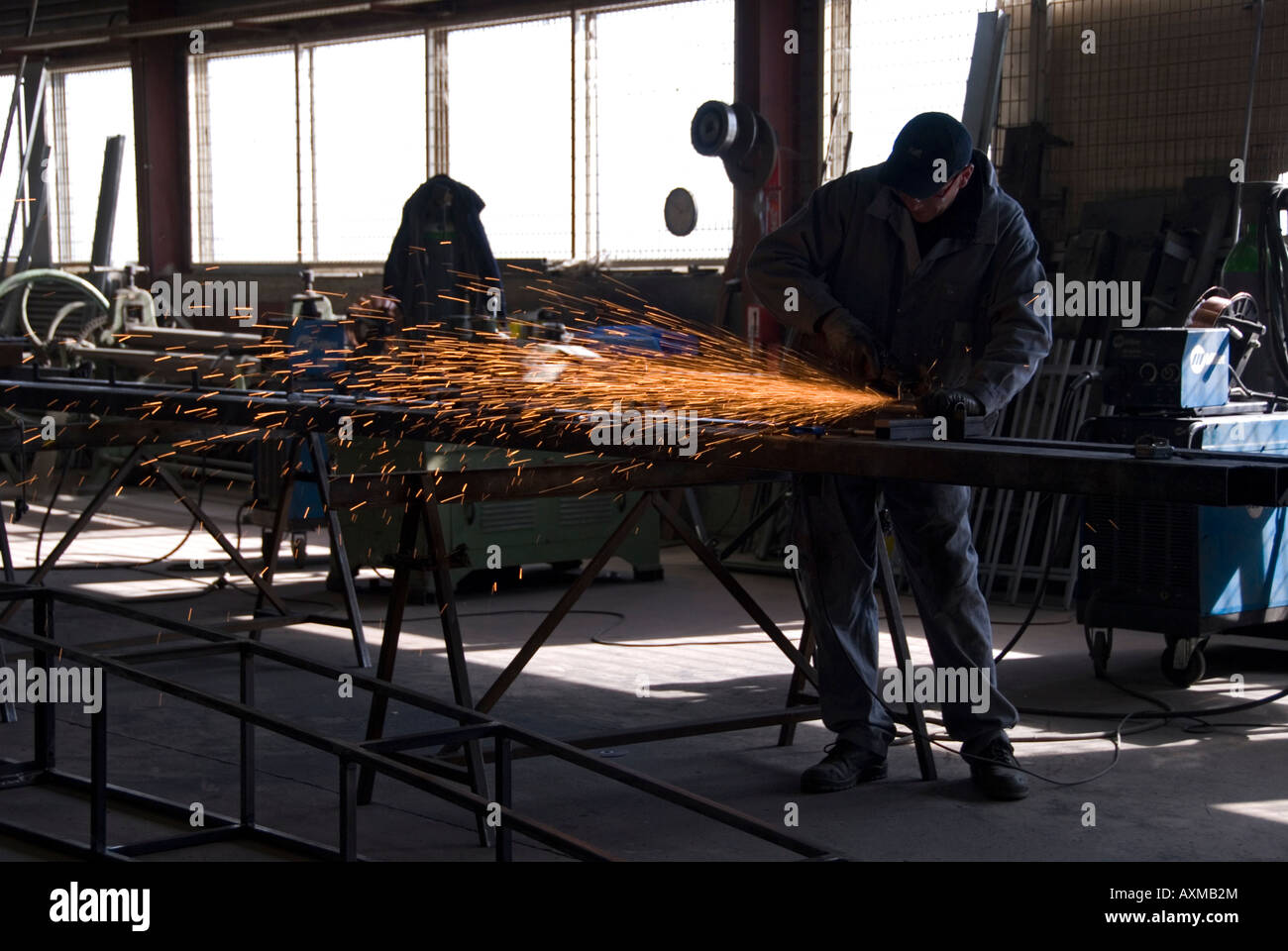 Stock photo of a factory worker grinding metal flat with an electric ...
